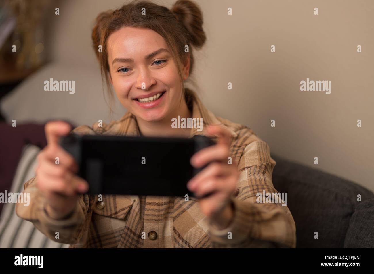 Joyful girl gamer plays mobile games on a portable game console. Close ...
