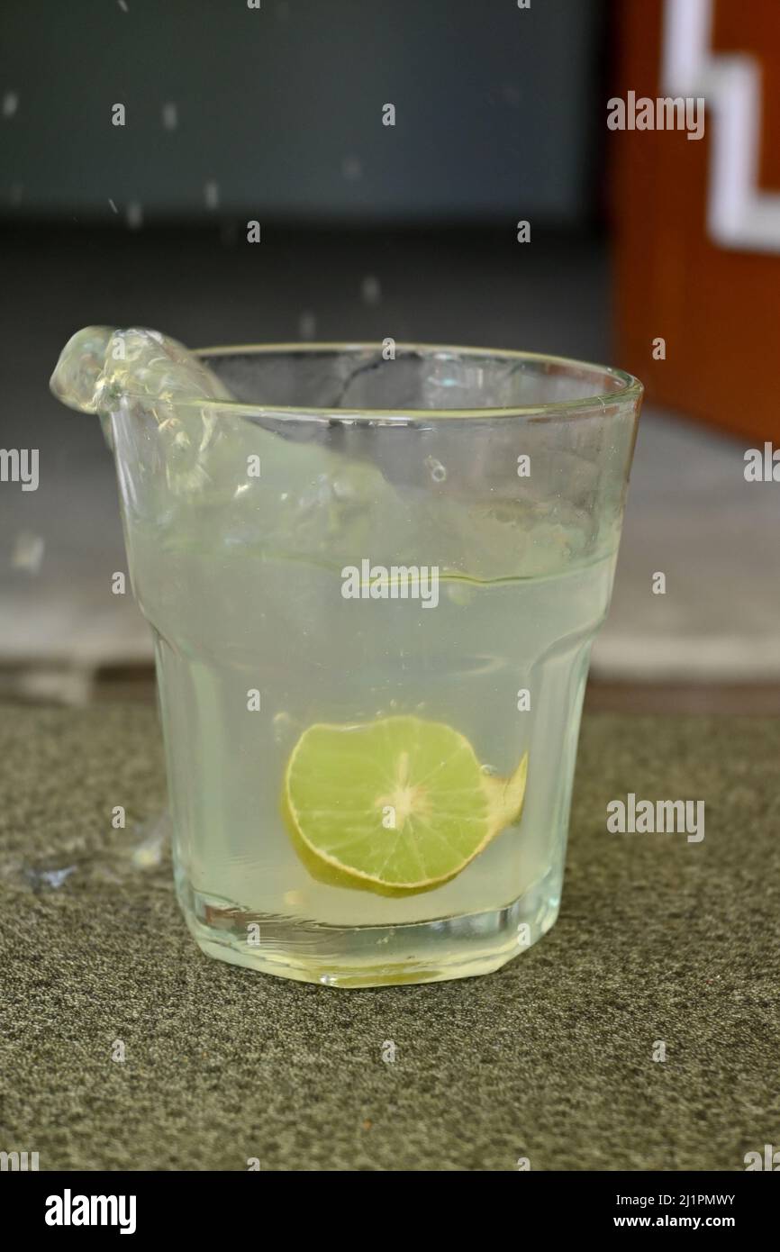 closeup the lemon juice flow in the glass over out of focus grey brown ...