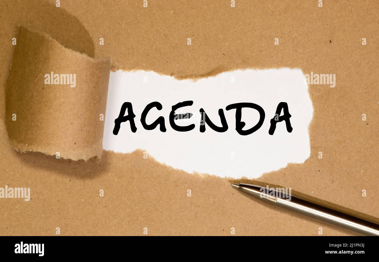 Text AGENDA appearing behind ripped brown paper Stock Photo - Alamy