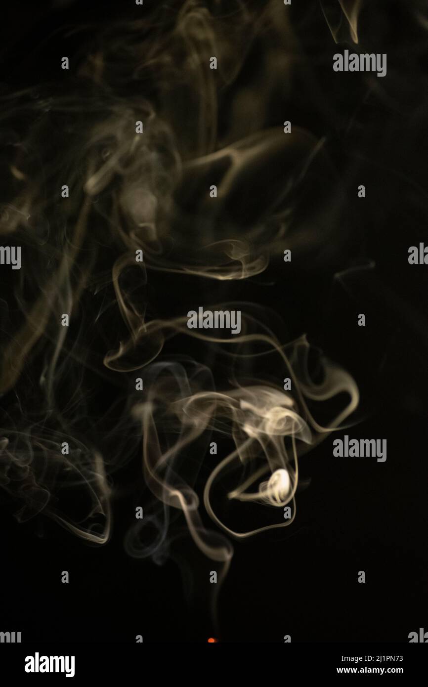 A golden yellow swirling, ascending smoke pattern on a black background ...