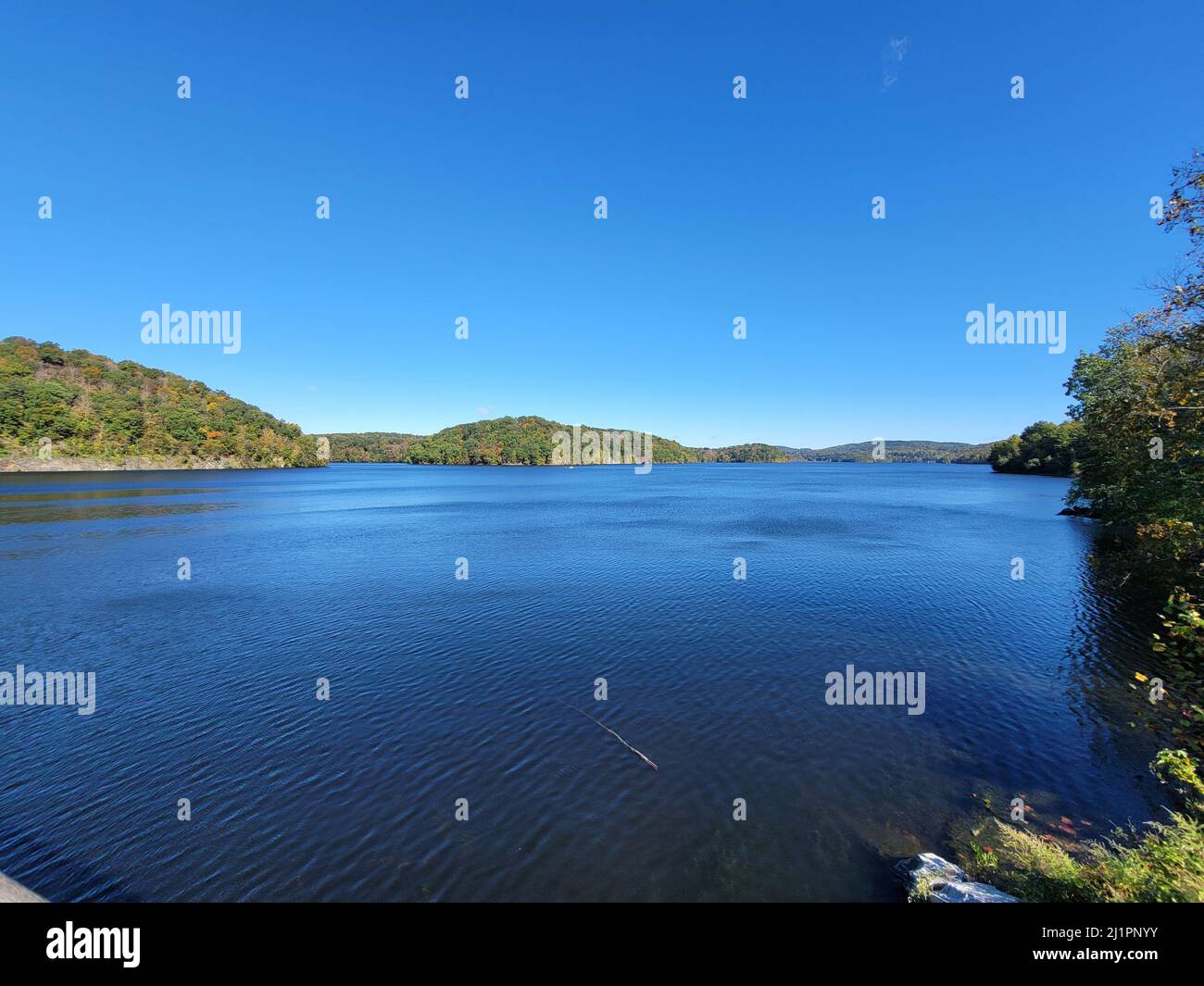 A beautiful landscape of blue lake near the dam with green hills and ...