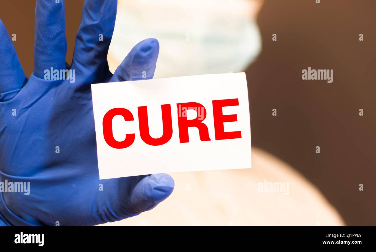 CURE word on white sticky note holding by woman in medical gloves ...
