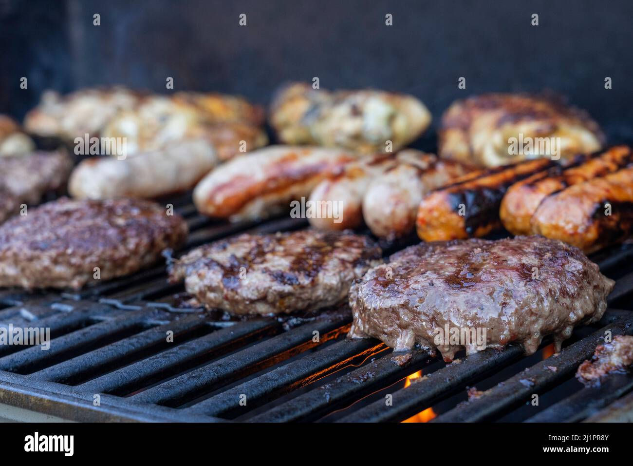 Burgers and sausages sizzling on a BBQ Stock Photo - Alamy