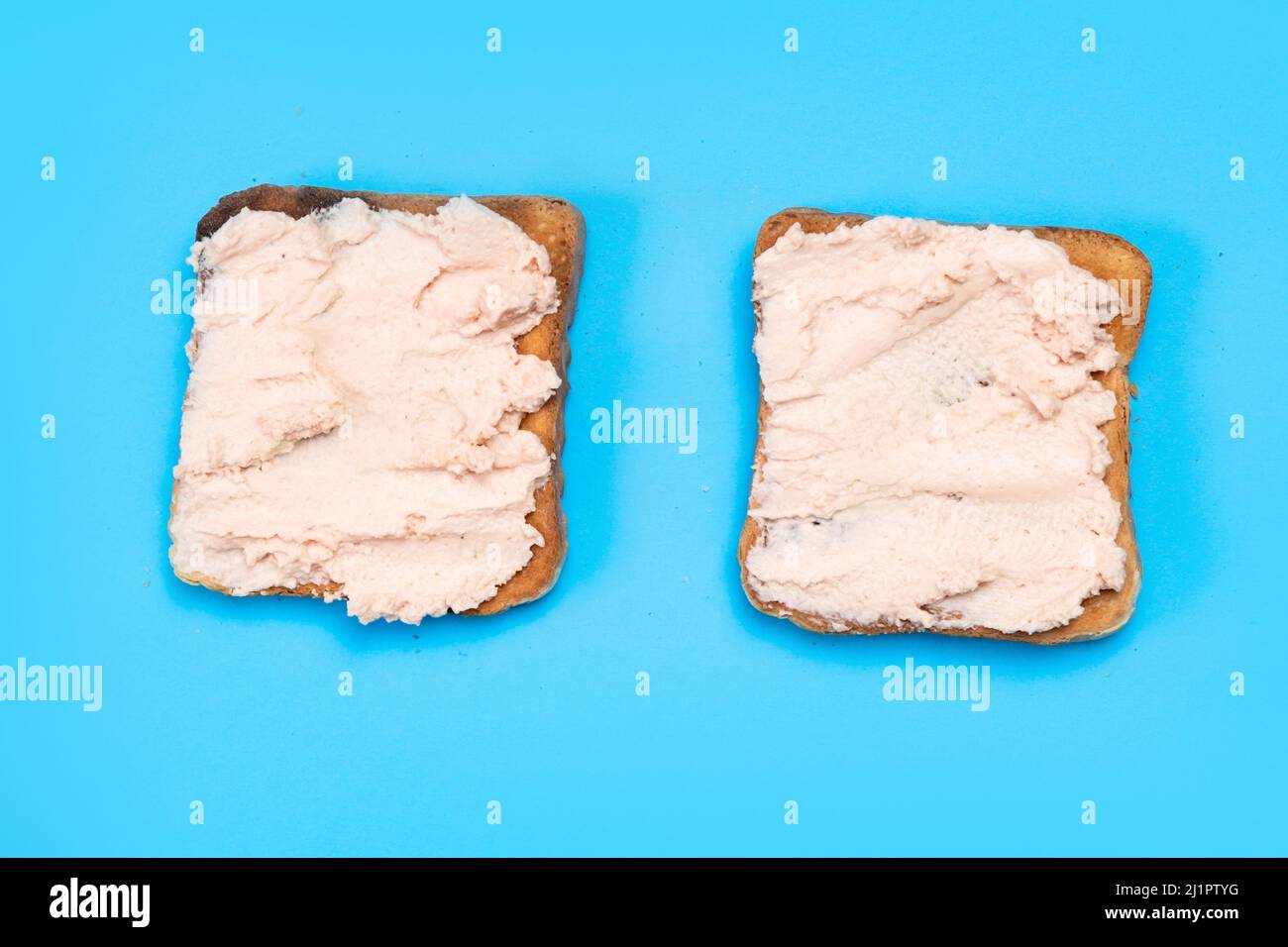 Two toasts with cream spread on a blue background. Food concept. Fish ...