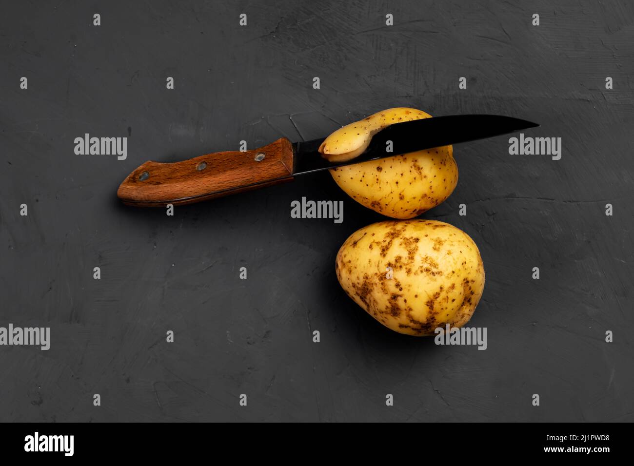 Potato and knife. Peeling potatoes. Dark background. Preparing for ...