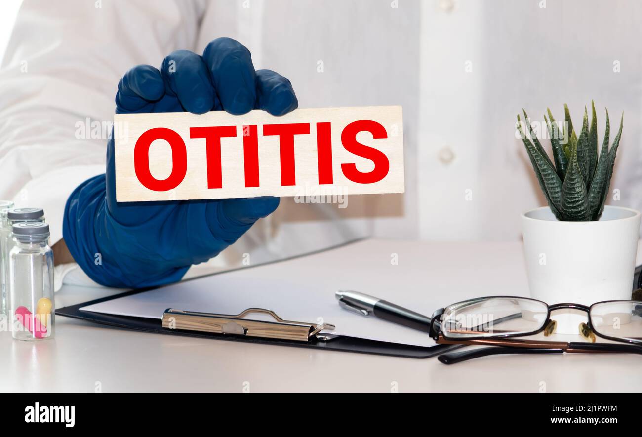 Doctor's hands in blue gloves shows the word otitis. Medical concept ...
