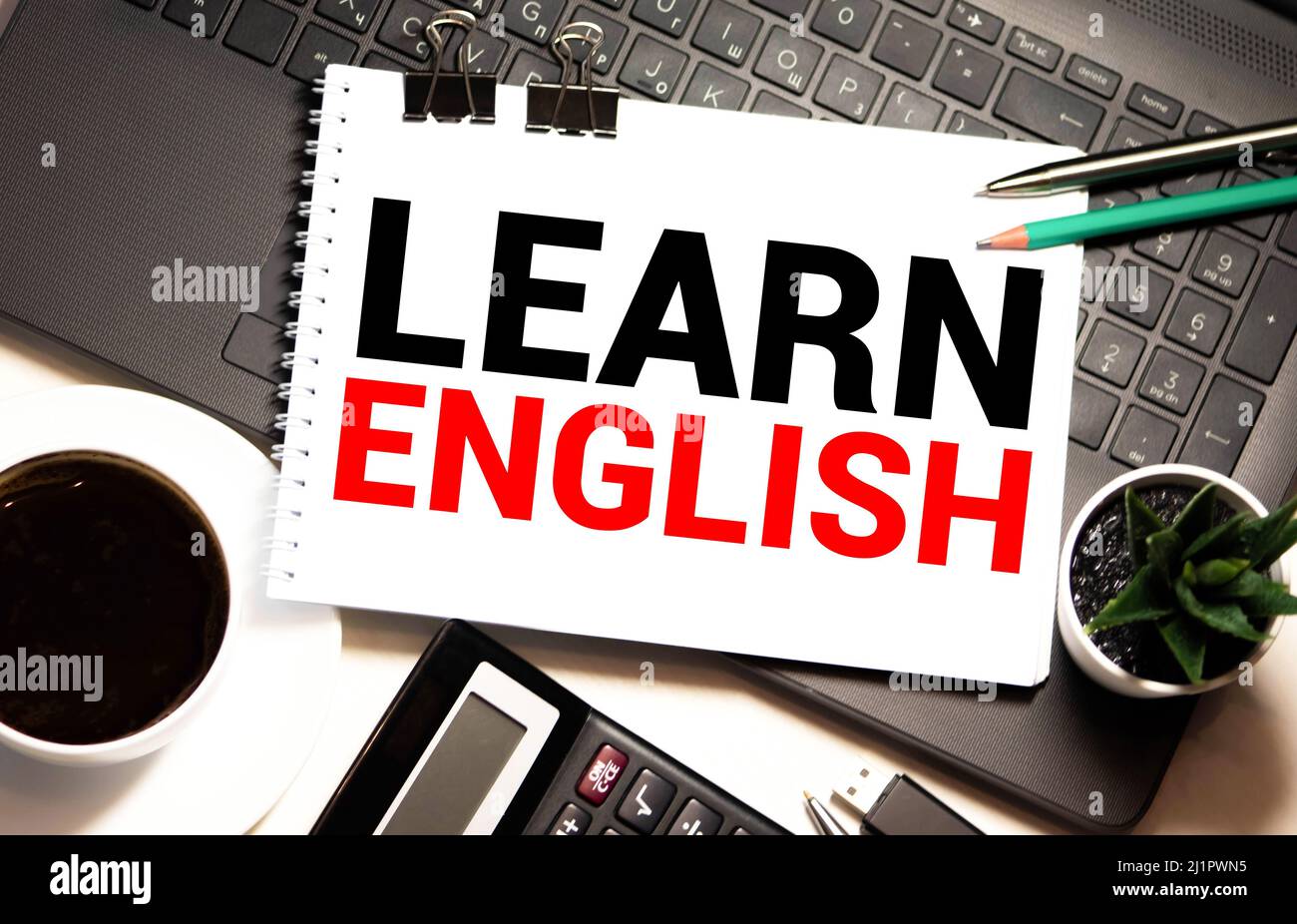 Learn English Text written on notebook page, red pencil and coffee cup ...