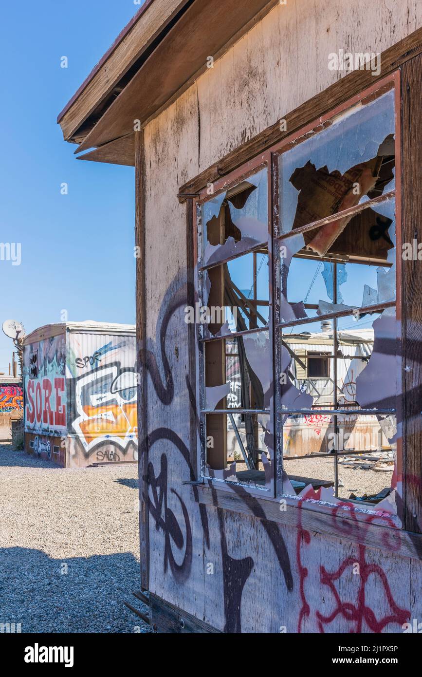 A vandalized house with broken window glass and spray painted graffiti ...