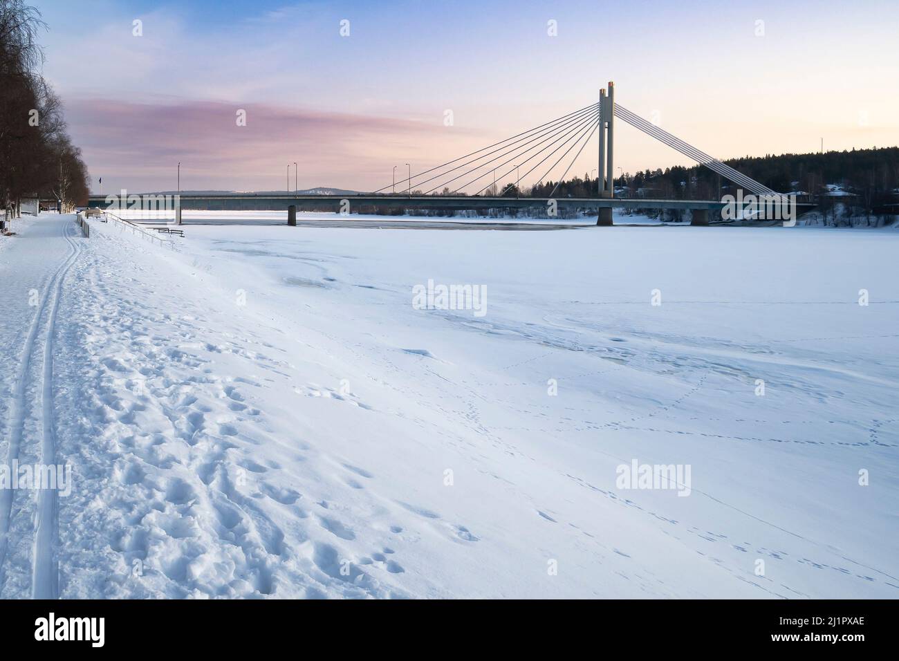 A bridge over the frozen Kemijoki river, Rovaniemi, Finland, at dawn ...