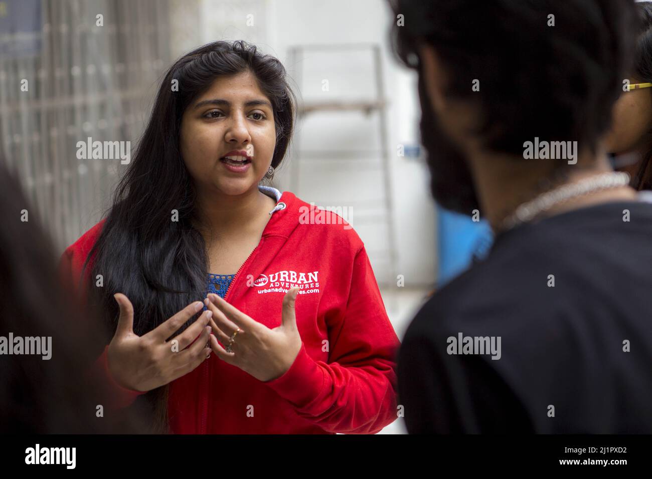 A young woman standing and talking to her peers and explaining ...