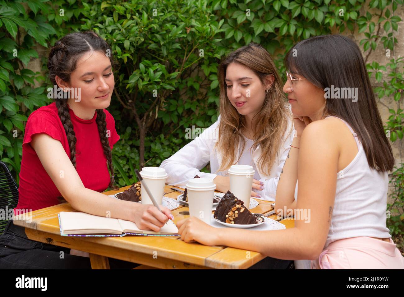 A three girlfriends in a cafe are eating dessert and having a nice ...