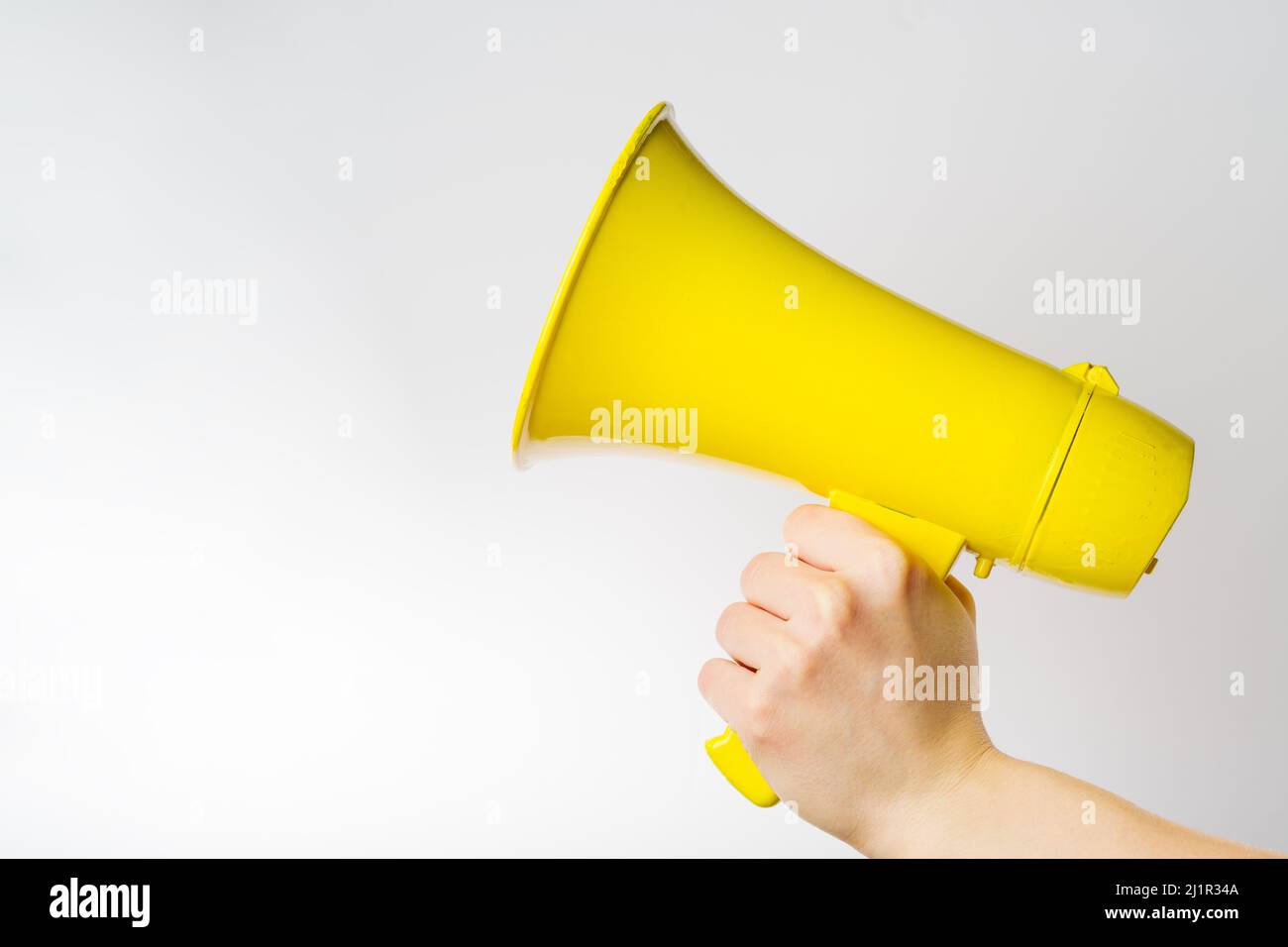 On a white background, a yellow megaphone in a female hand. Symbol of ...