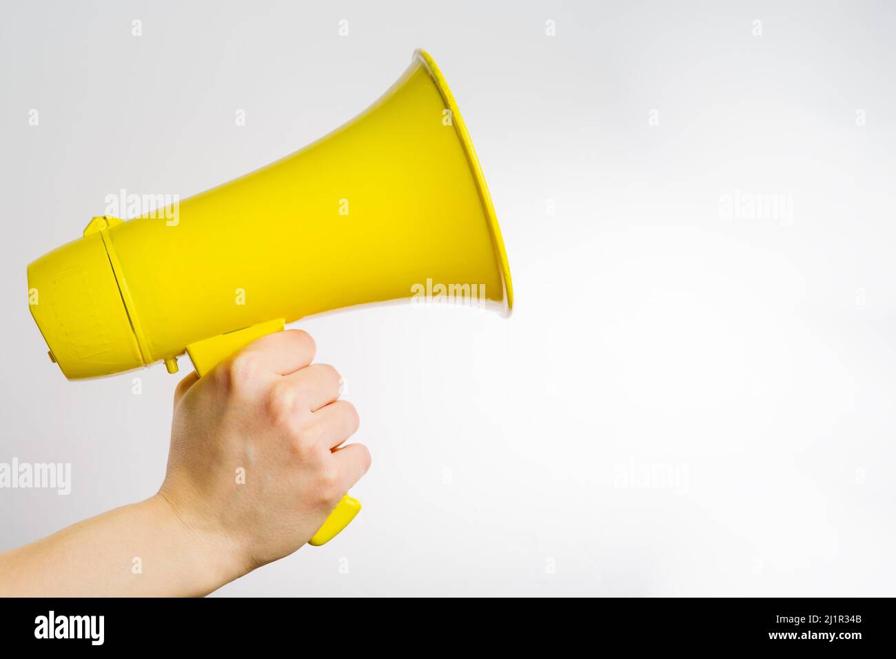 Yellow megaphone in a man's hand on a white background. Minimalism ...