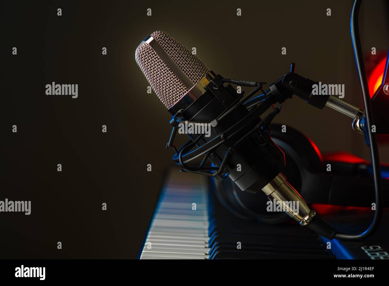 A modern microphone lies on a midi keyboard on a brown background ...
