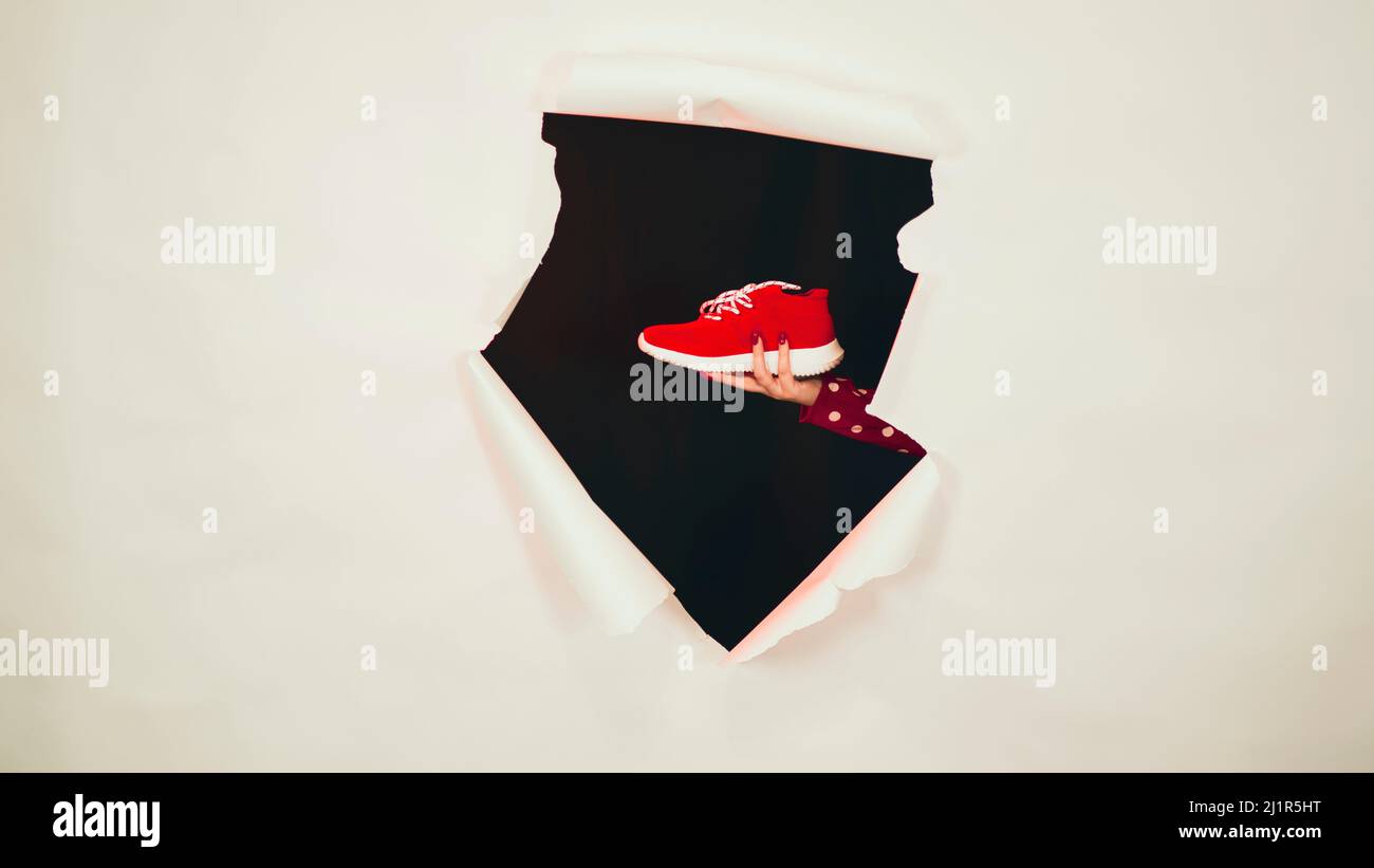 Woman's hand with one shoe in hole of white background. Unrecognizable ...