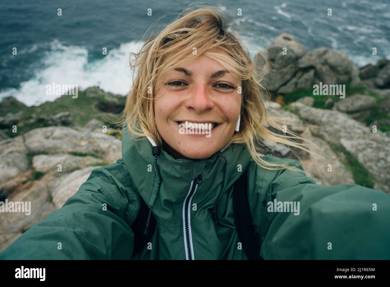a girl takes a selfie in a jacket on the background of the sea in bad ...
