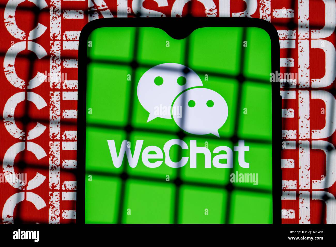 WeChat messenger logo on the smartphone screen behind the bars on the ...