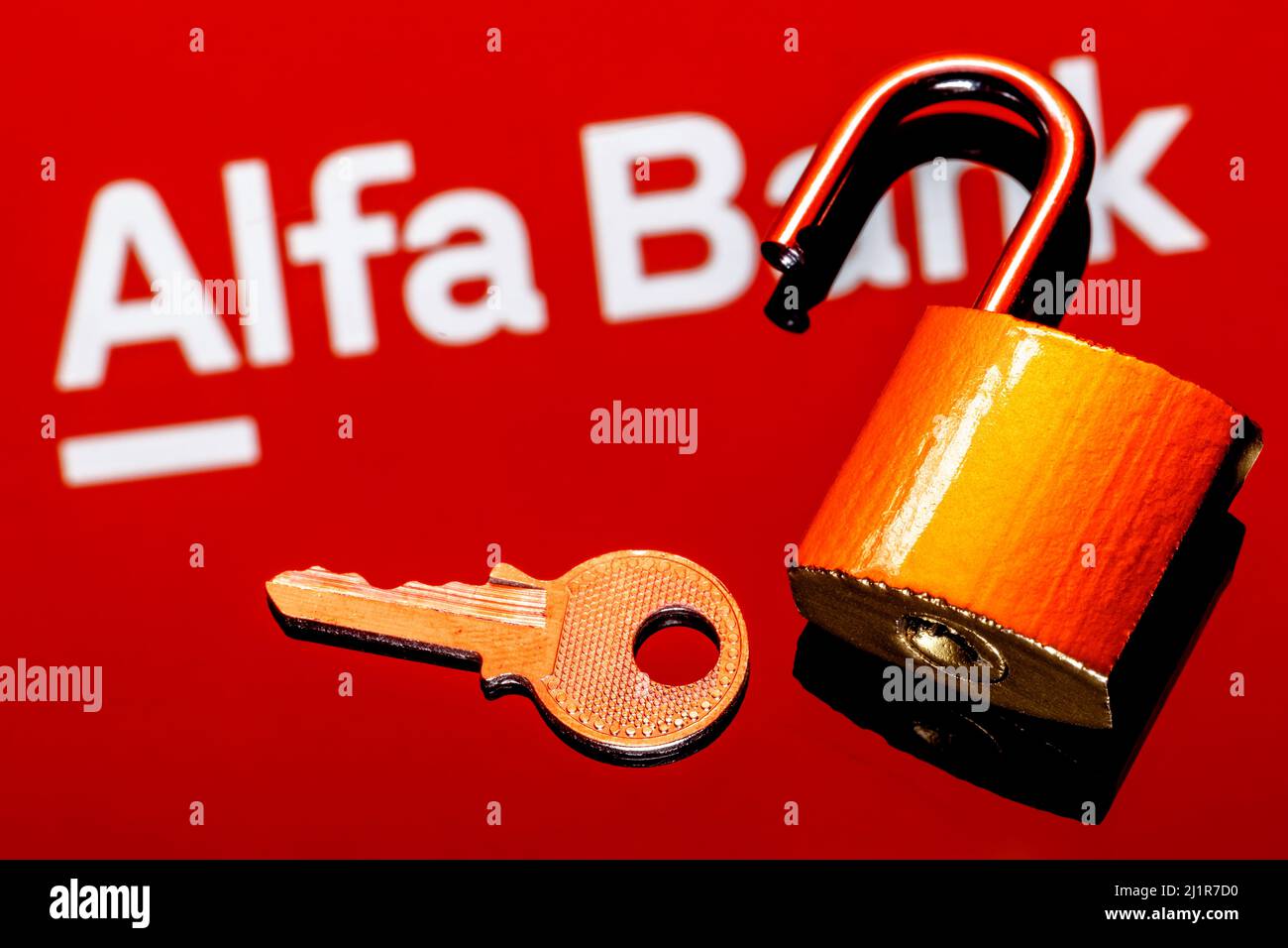 An open security lock and key on background of Alfa Bank logo in mirror ...