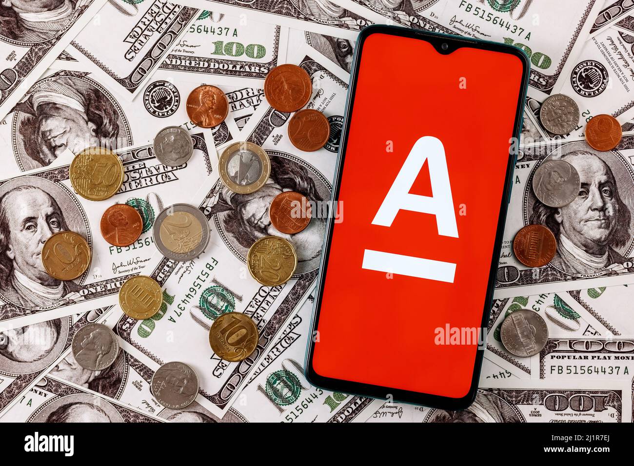 Smartphone with Alfa Bank logo surrounded by variety of metal coins on ...