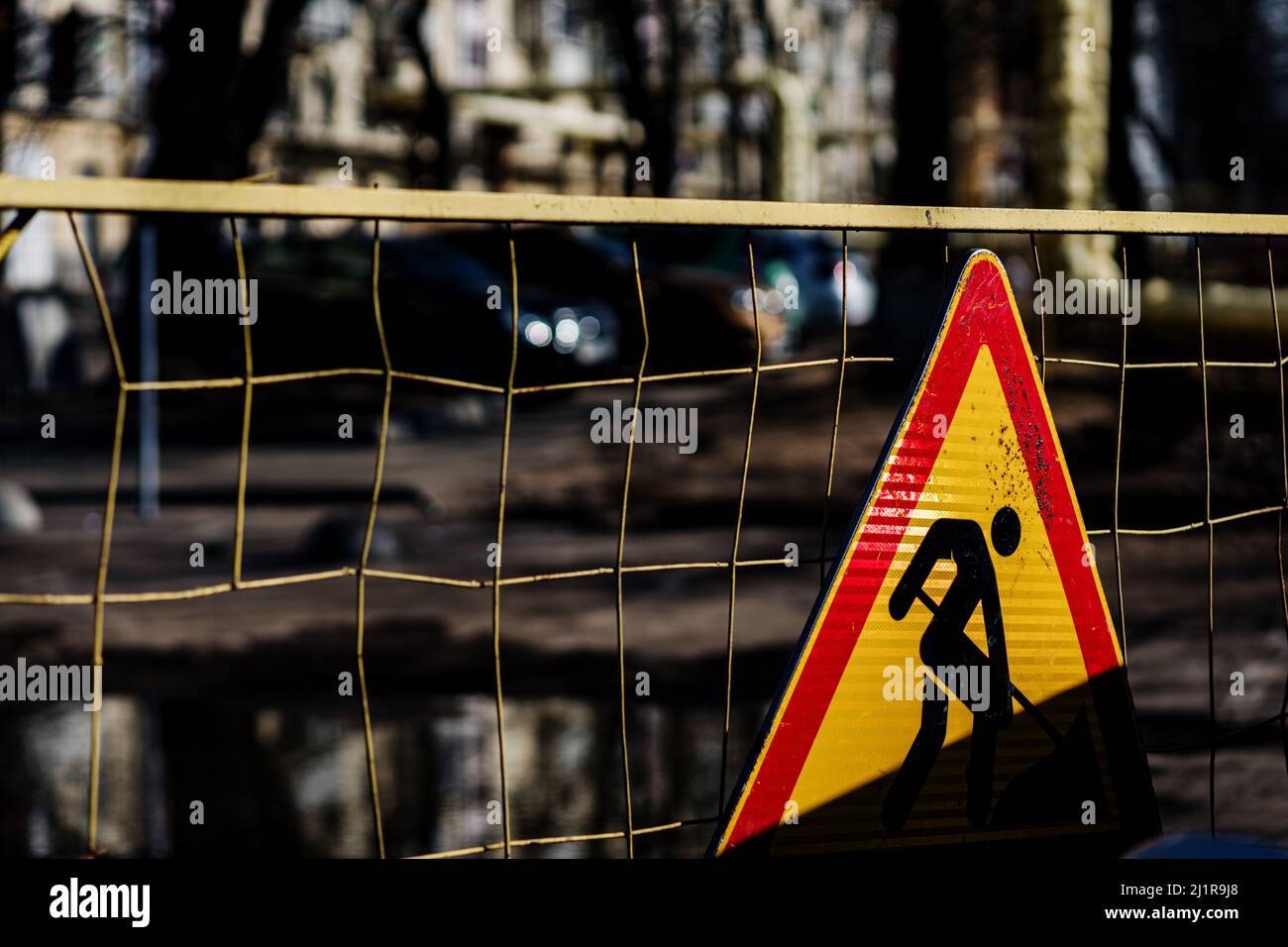 Roadworks, under construction. Earthwork sign on fence with trench hole ...