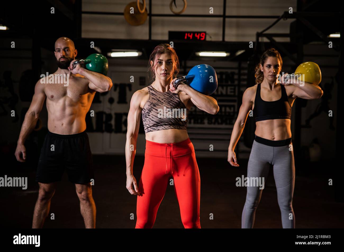 Group training in a modern and fully equipped gym. Three friends lift ...