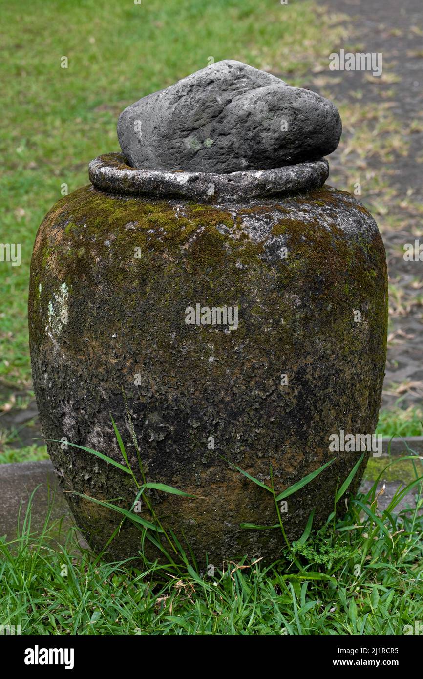 Old concrete vase with large stone lid sitting outside on ground, still ...