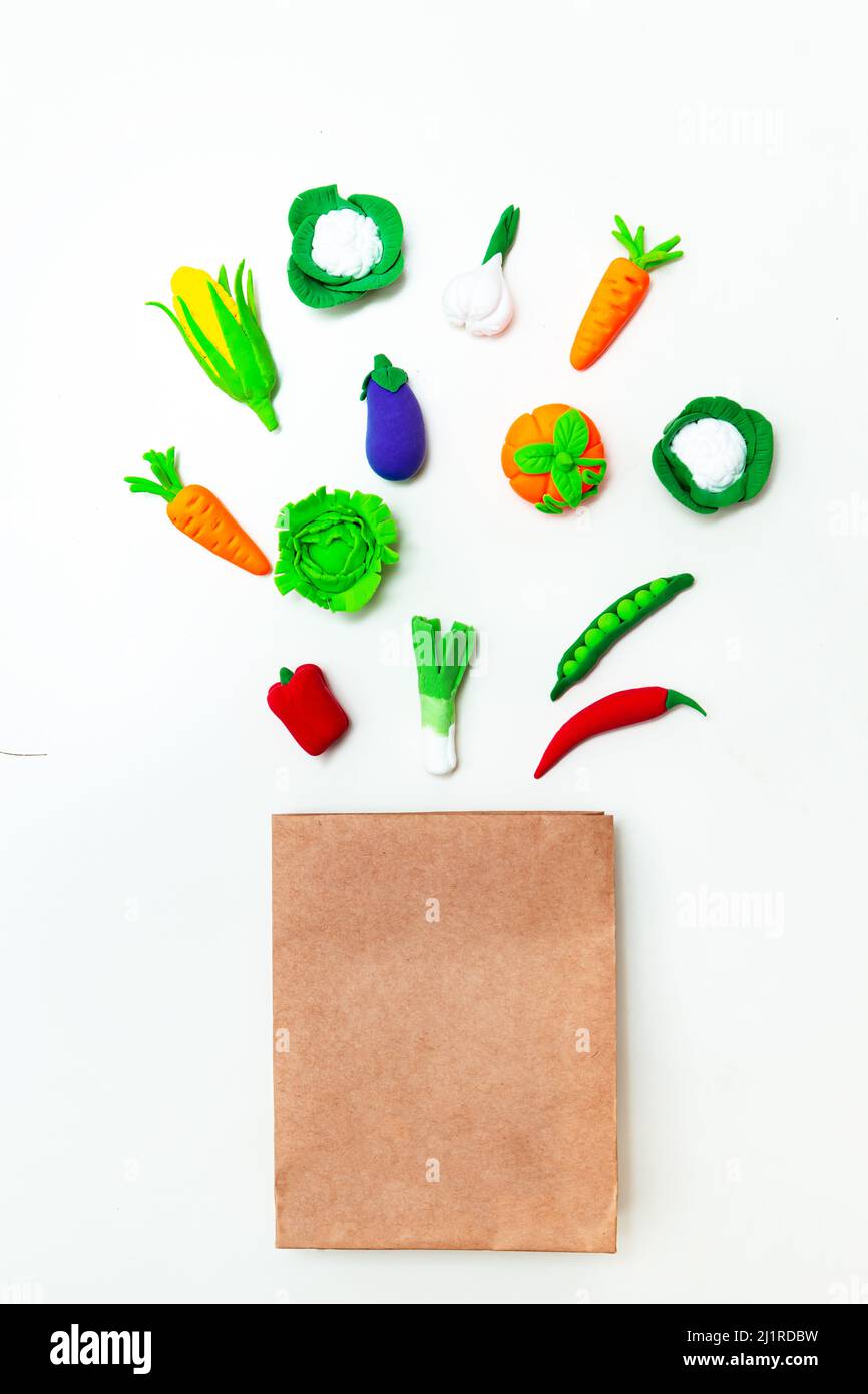 Plasticine vegetables fly into a craft bag. White background. Ecology ...