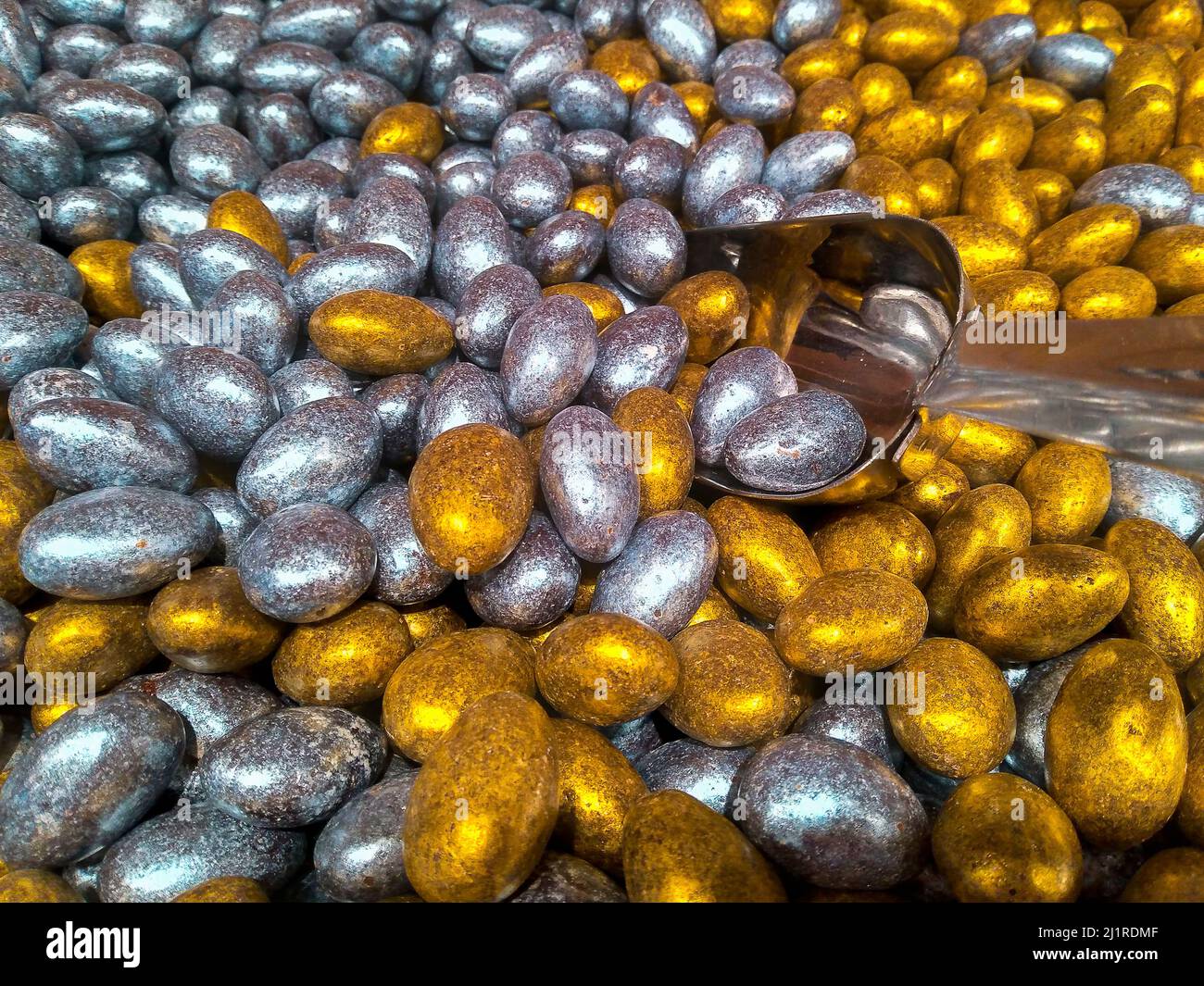 Metal scoop with colorful glazed in gold and silver chocolate candies ...