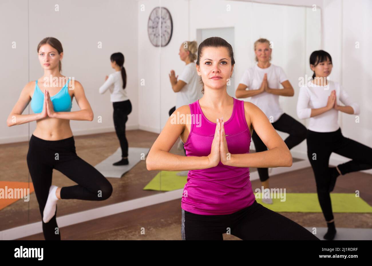 Group of young women training yoga positions in modern yoga studio ...