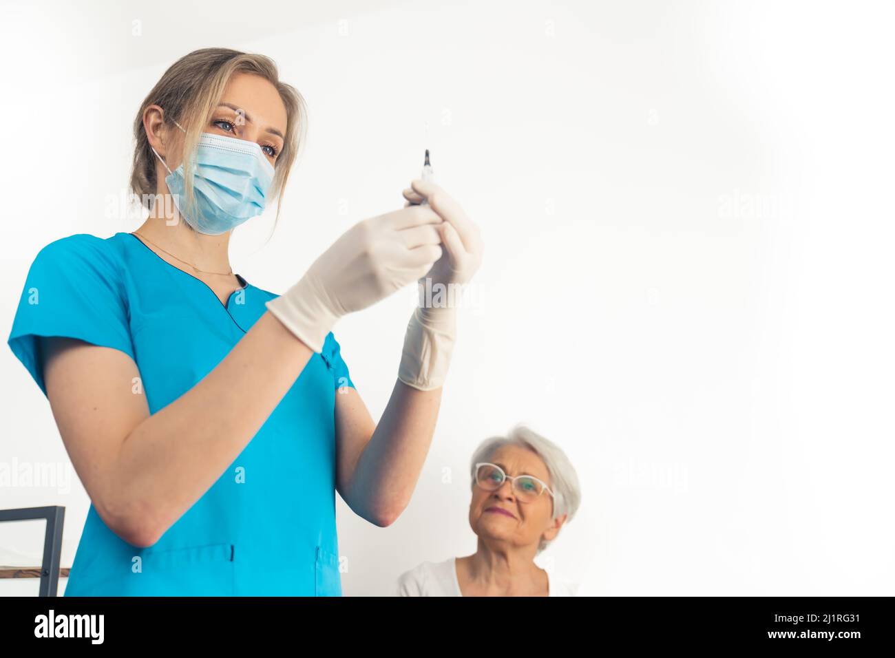 Young nurse prepares an injection for elderly pensioner lady patient ...