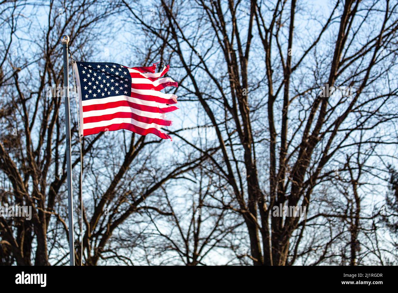 Badly torn American flag flying from flagpole outside Stock Photo - Alamy