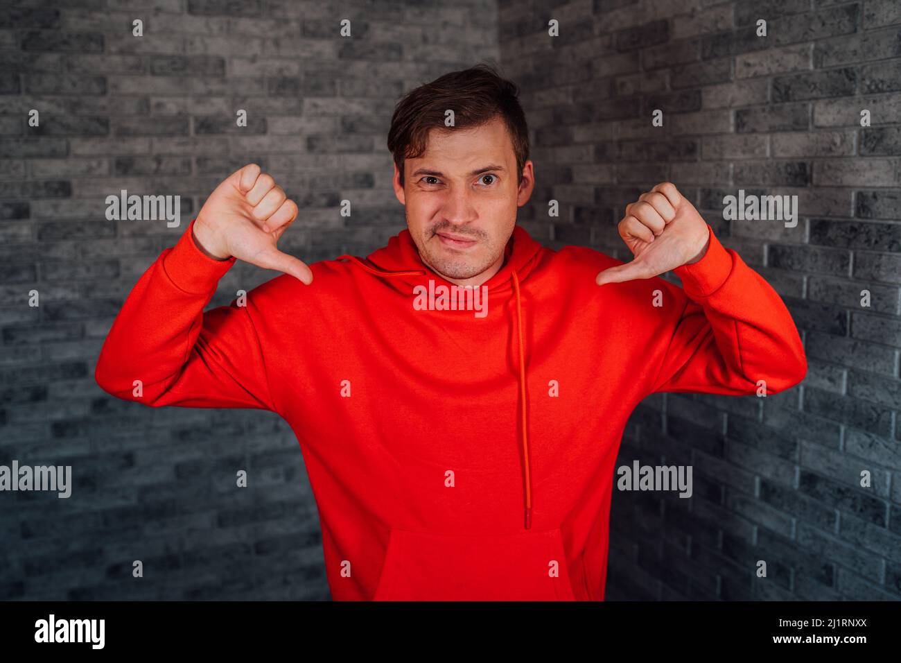 A man shows a gesture of disapproval on a brick background. The concept ...