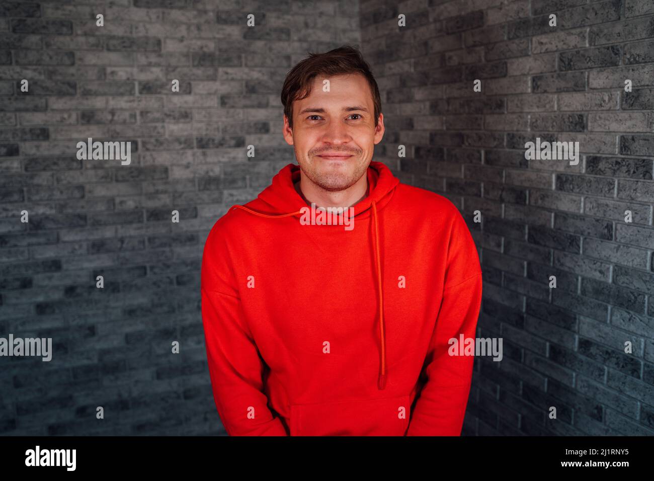 A beautiful emotional man in a red hoodie is happily surprised with ...