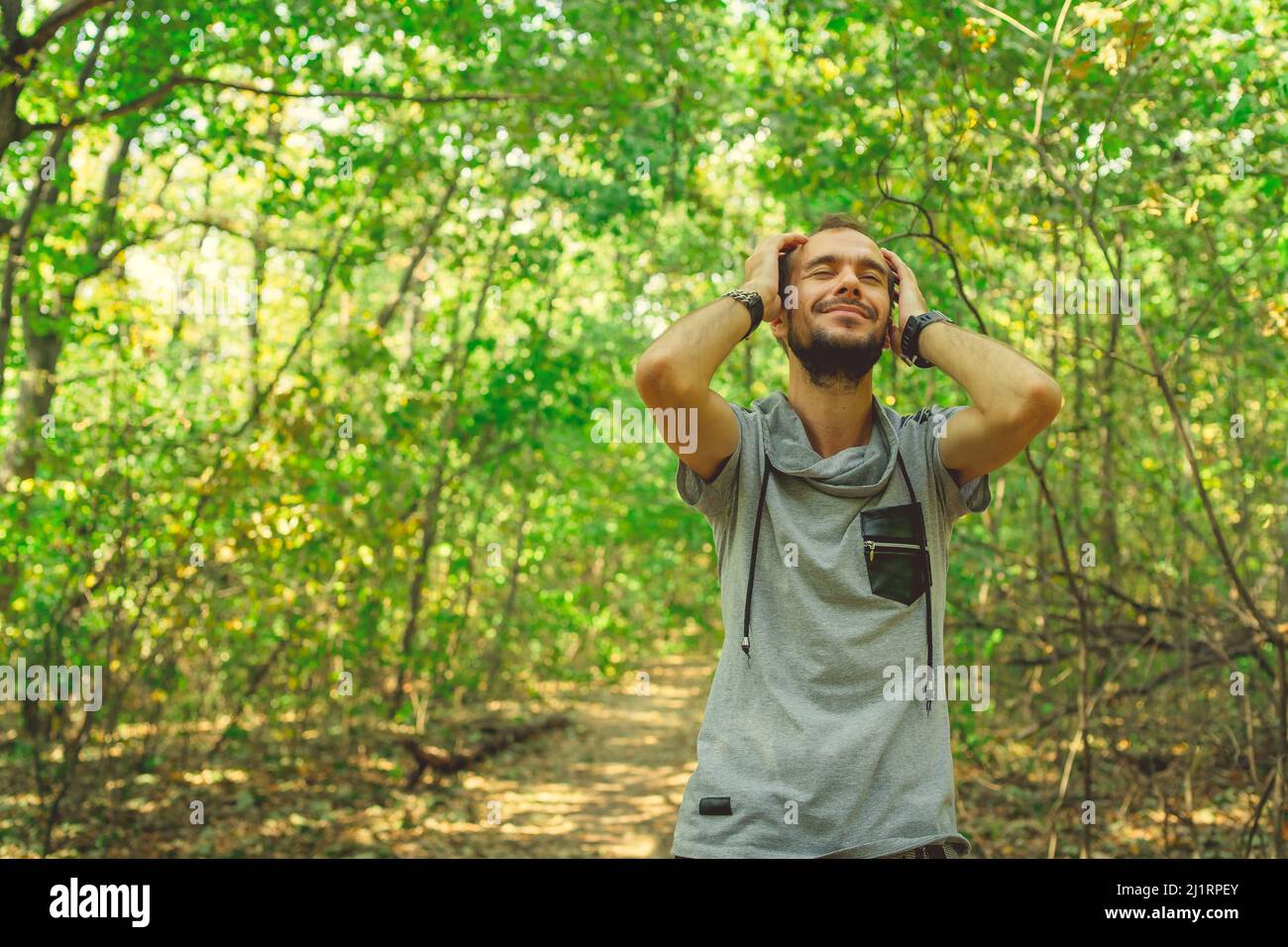 A man experiences ecstasy, standing in the woods and holding his head ...
