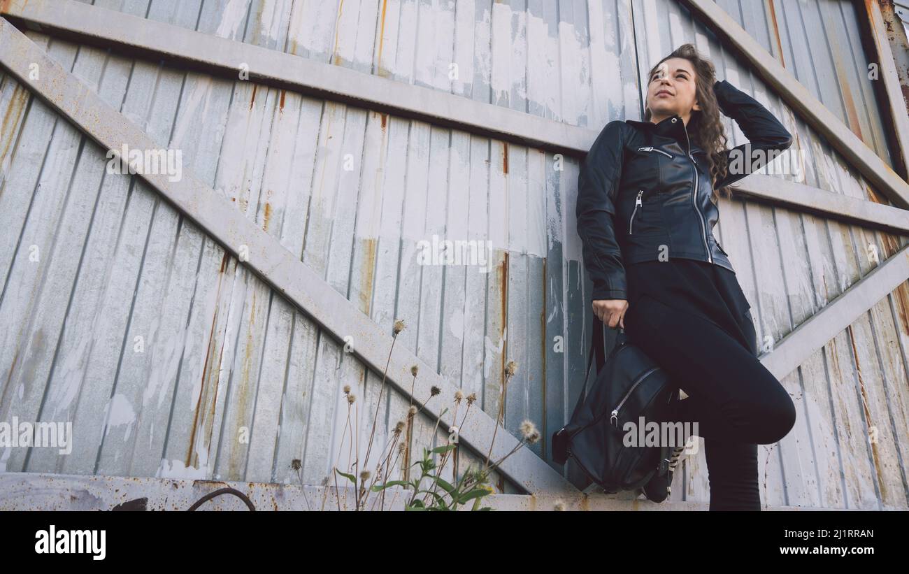 A beautiful young woman in casual clothes is posing against the ...