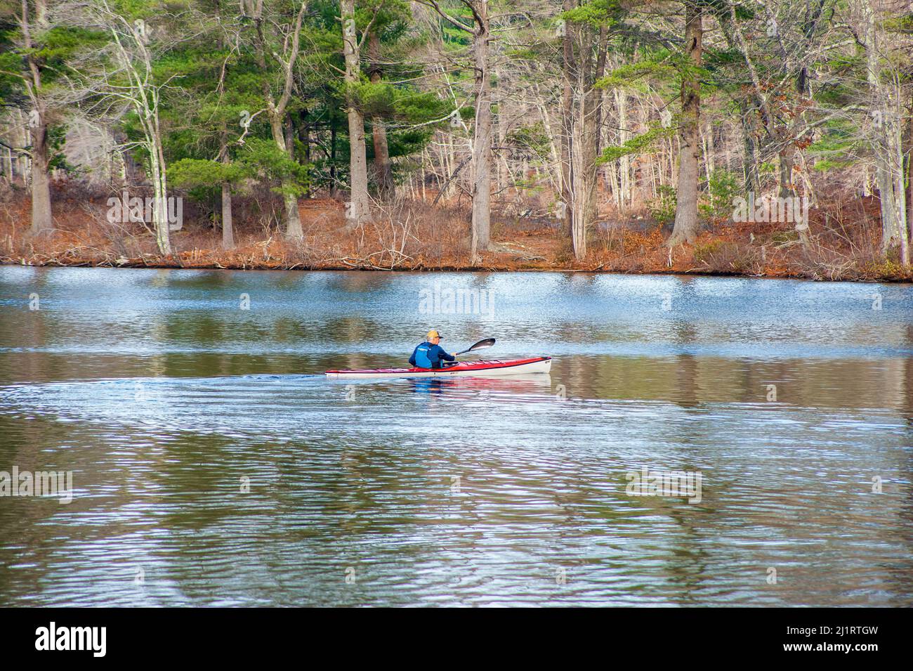 A man in his 50s kayaking on a lake in early spring, with a ...