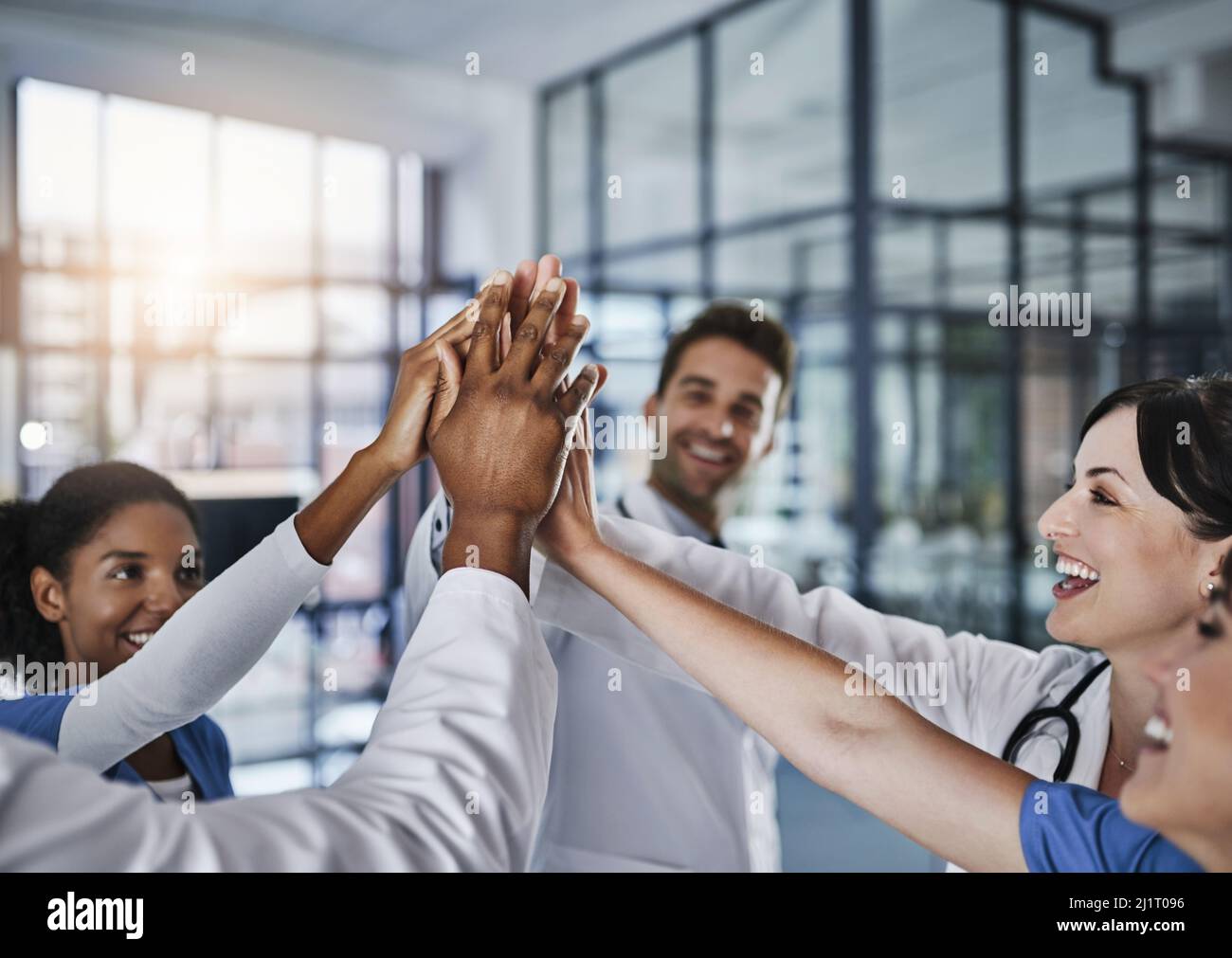 Heres to saving more lives. Shot of a group of doctors joining their ...