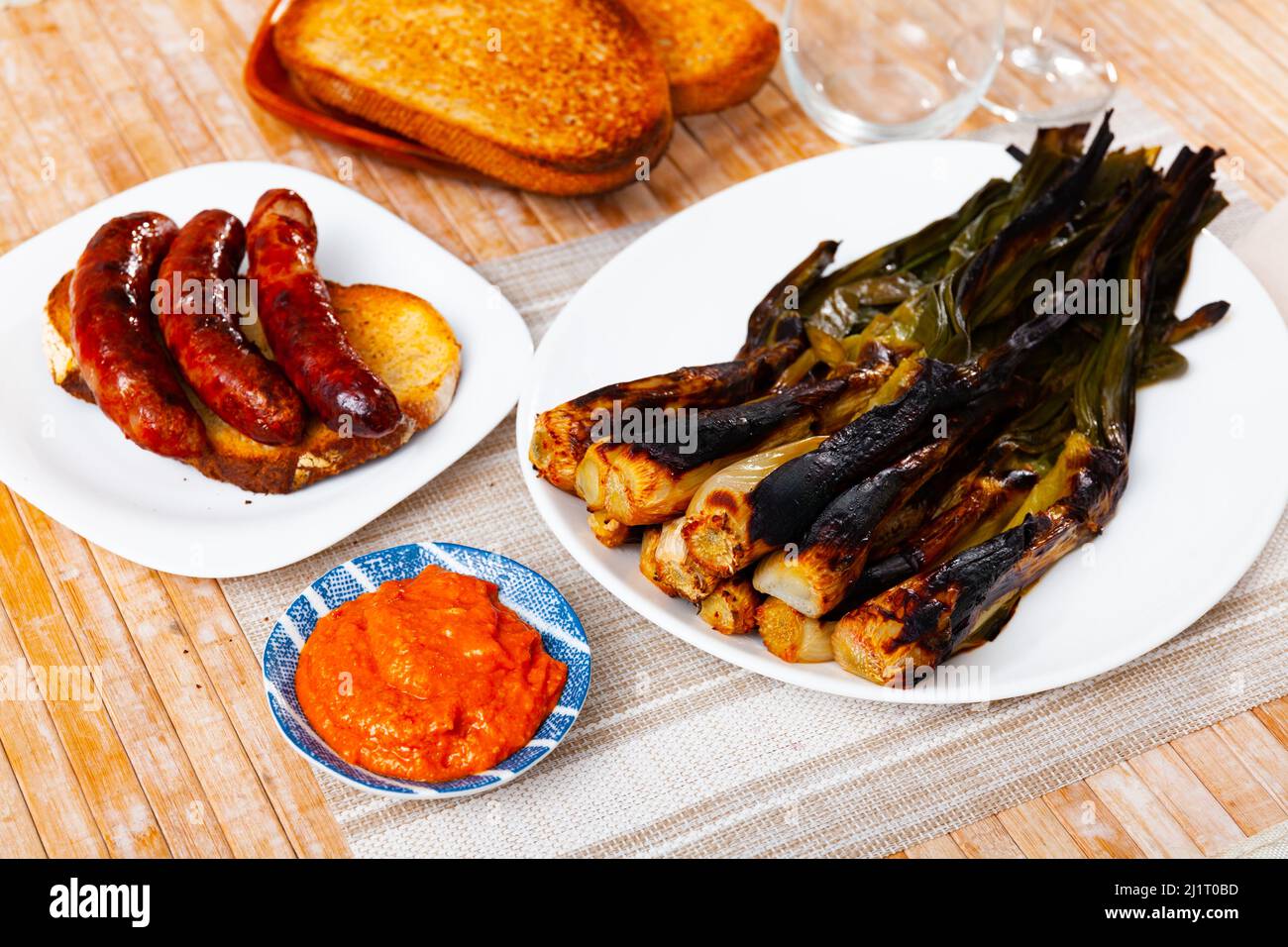 Calcot with romesco sauce and grilled botifarra Stock Photo - Alamy