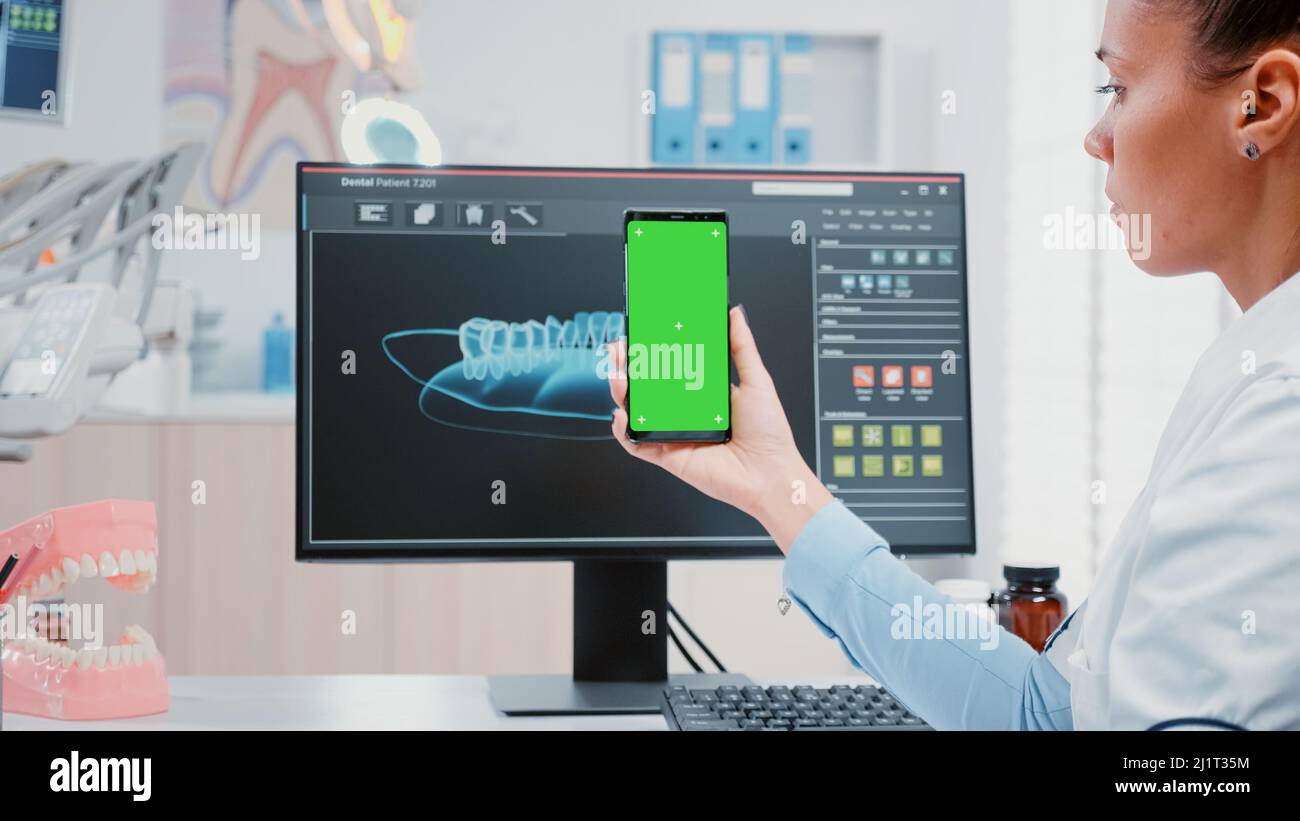 Woman working as dentist with green screen on smartphone in oral care ...