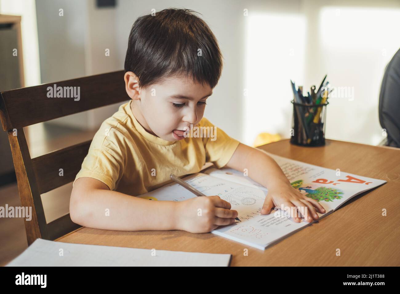 Boy making facial expression studying hard as he doing homework ...