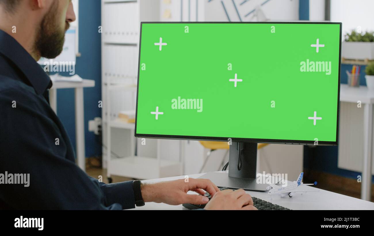 Close up of man typing on keyboard with green screen on monitor ...