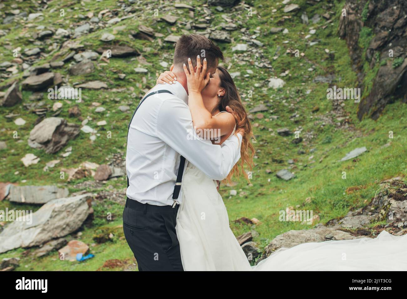 Brides hugging and kissing while posing for a photo on the rocky ...