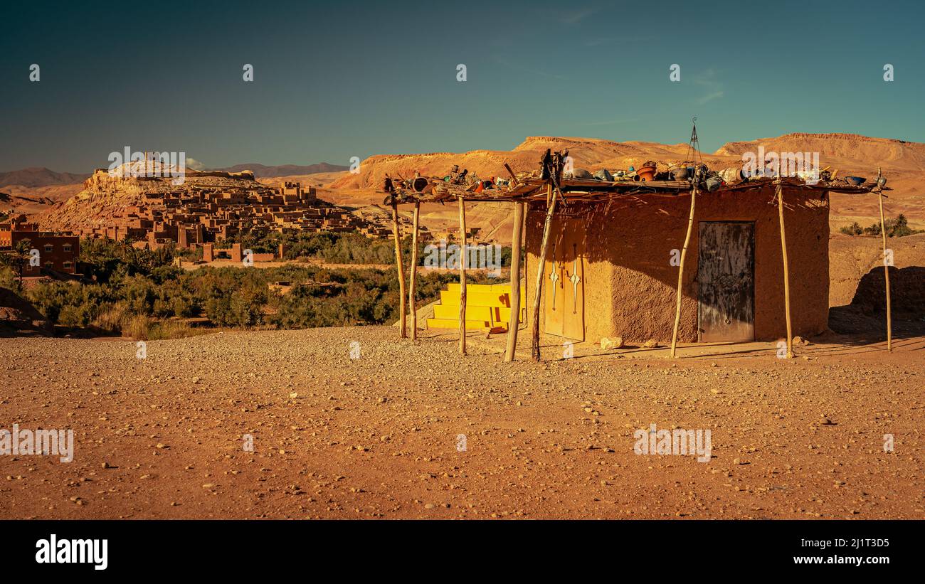 An old clay hut with a historical town in the background in Ait ...