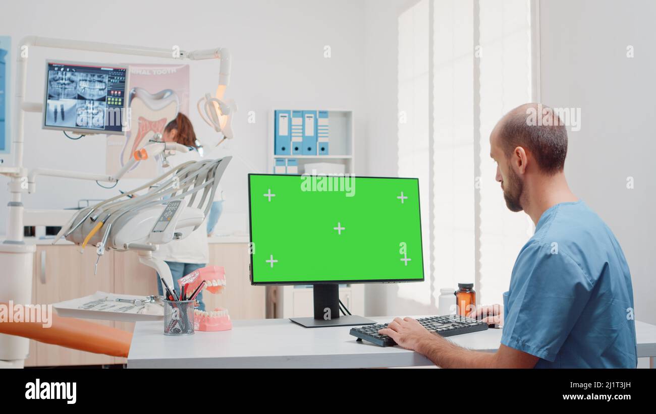 Man working with keyboard and computer with green screen on desk in ...