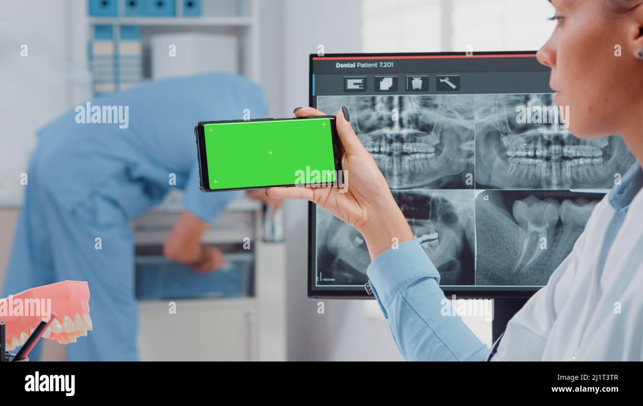 Close up of dentist analyzing smartphone with green screen and teeth ...
