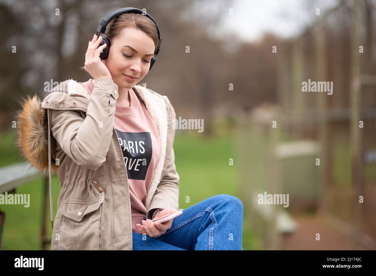 cheerful energetic girl, on a walk in the park with headphones and a ...