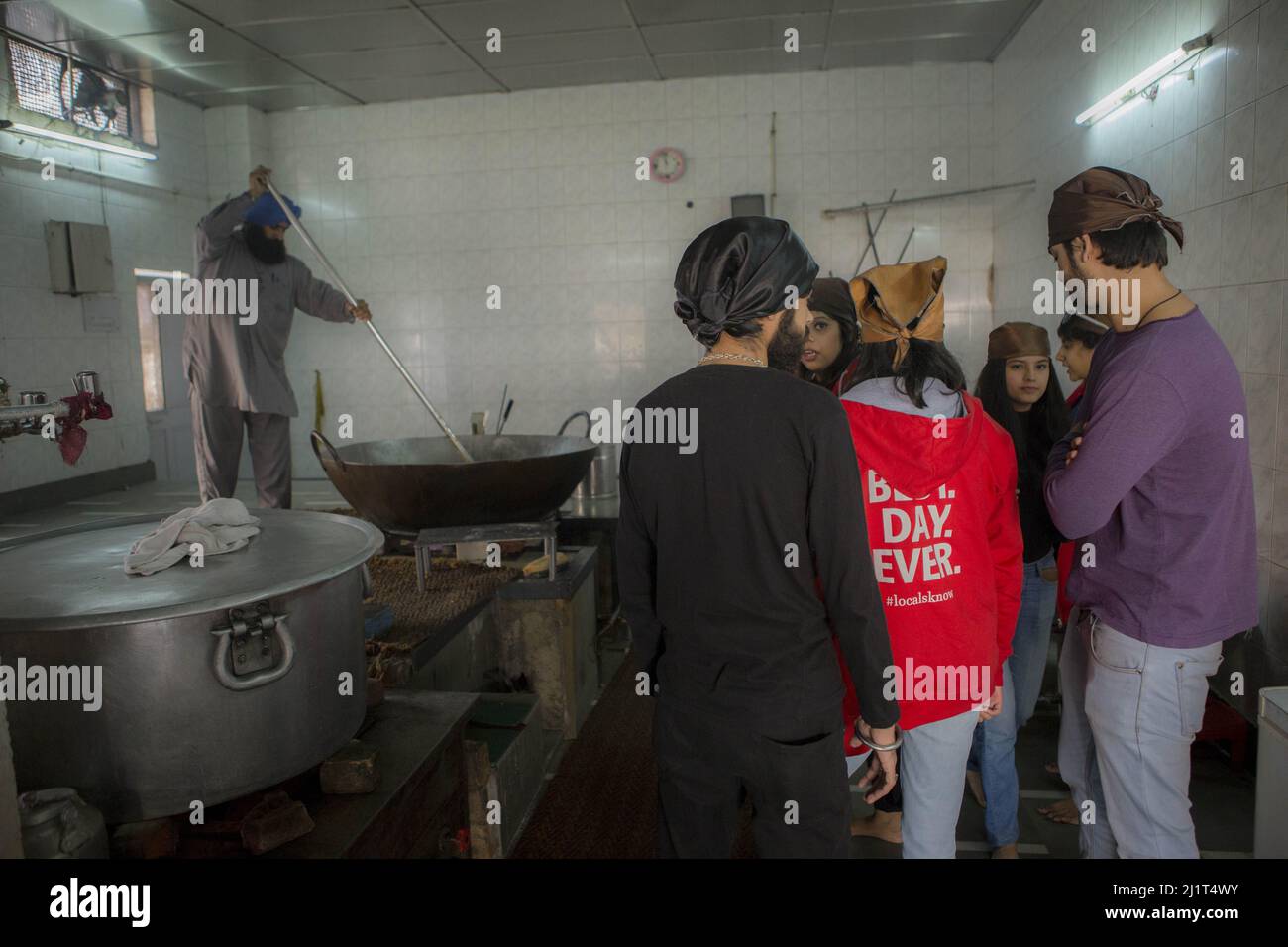 A group of tourists and locals with a Sikh man cooking in the ...