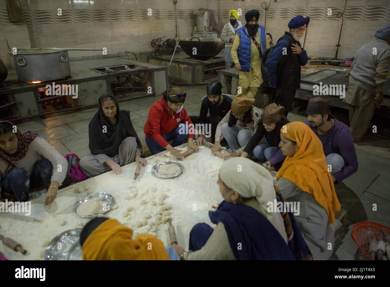 A view of tourists helping local women making traditional food with ...