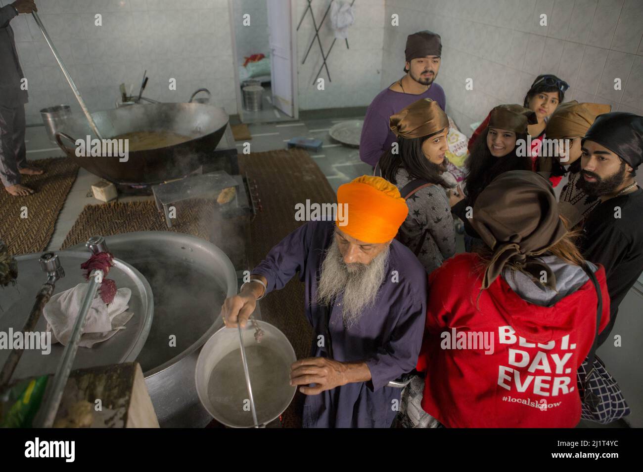 A group of tourists and locals with a Sikh man cooking at the free ...