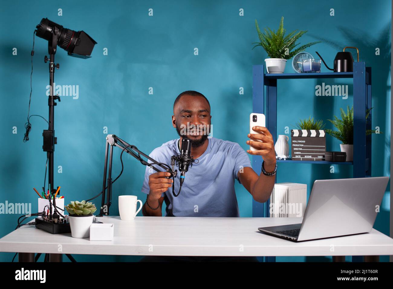 Vlogger sitting in vlogging studio holding microphone taking a selfie ...